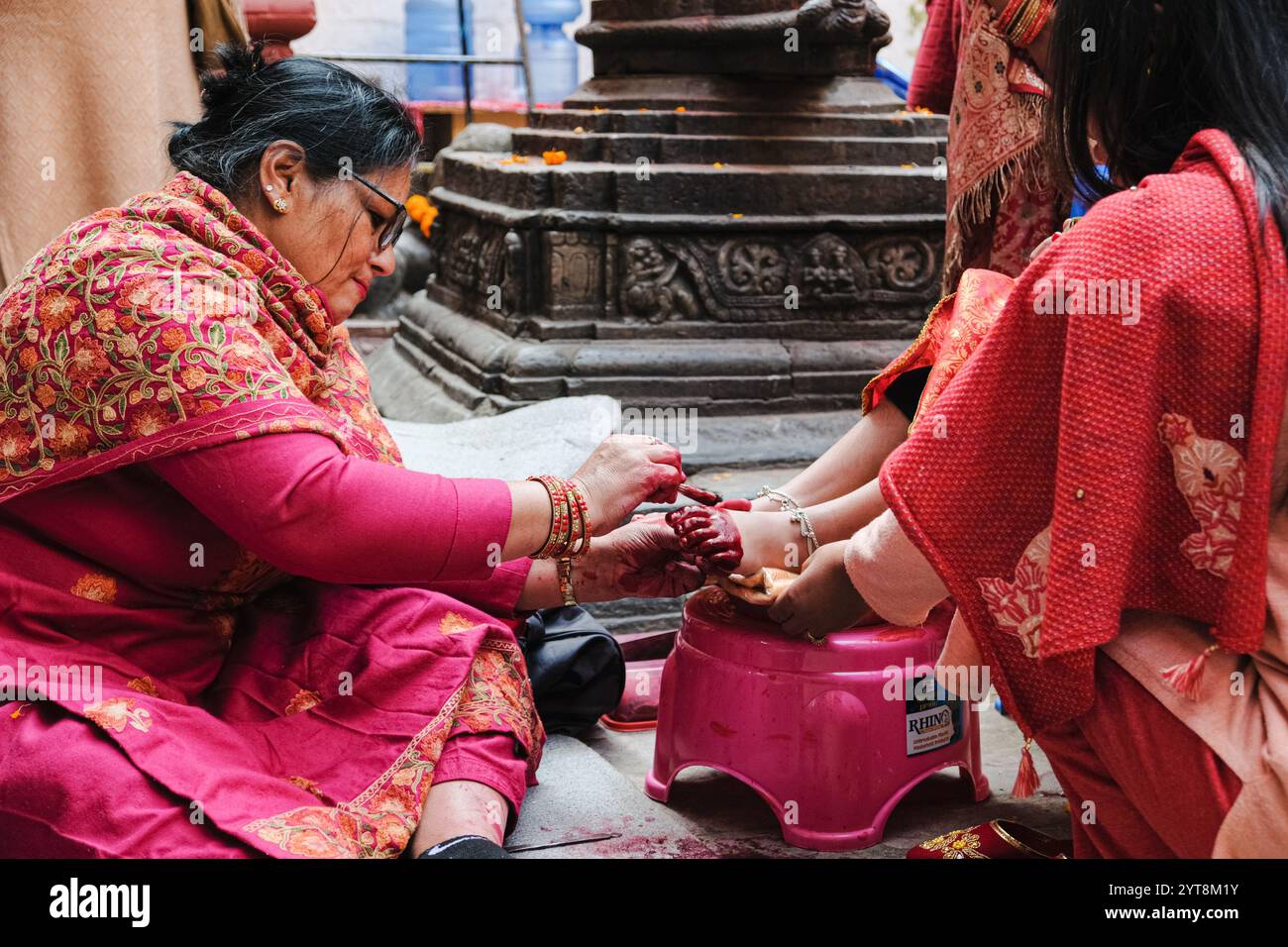 Thamel, Nepal. 6th Dec, 2024. A Newari woman paints a lady's feet at ...