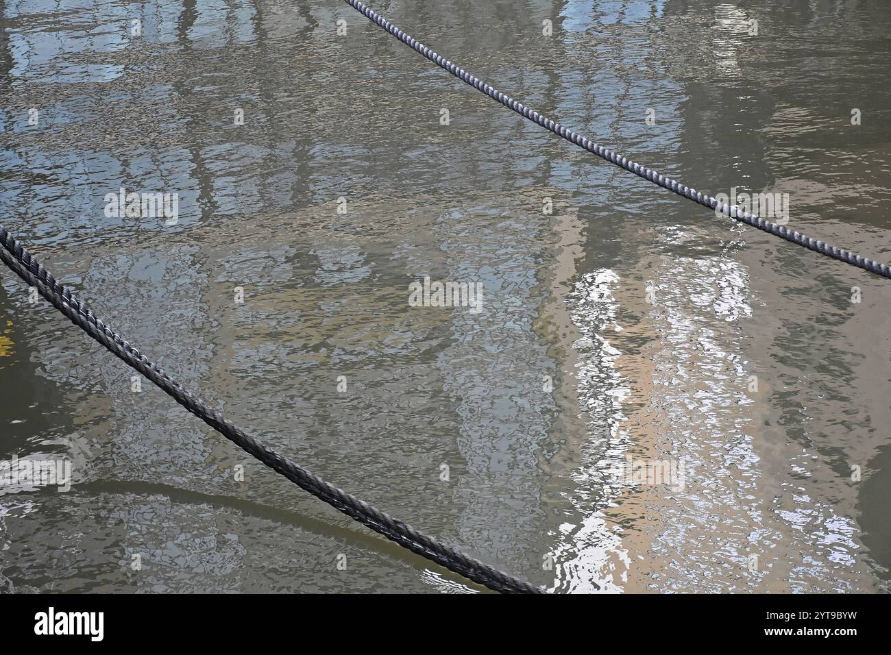 Ship ropes hanging over the water reflecting a house facade Stock Photo ...