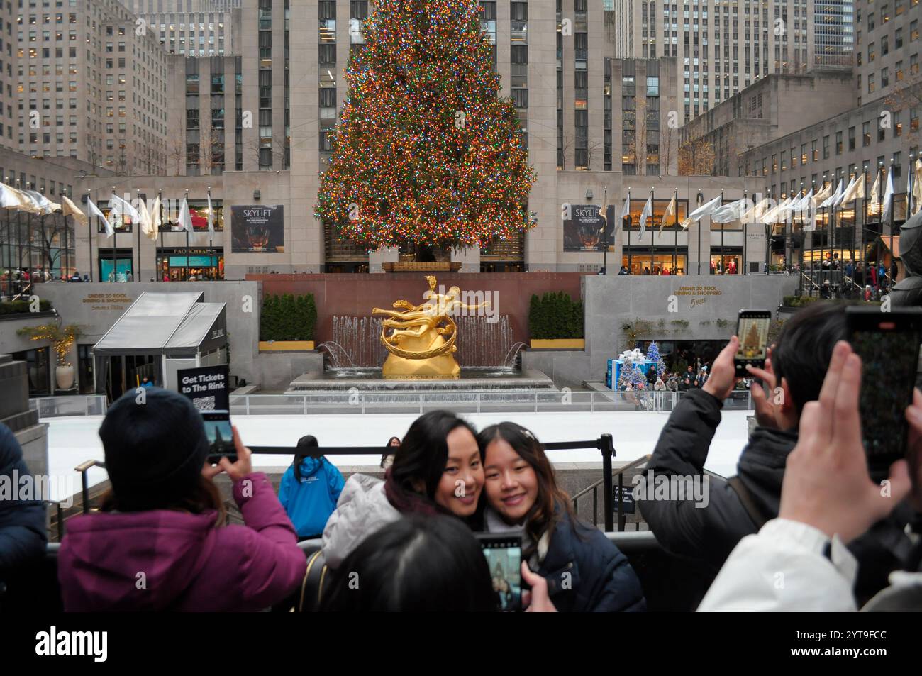 People take photos in front of the ice skating rink in Rockfeller ...