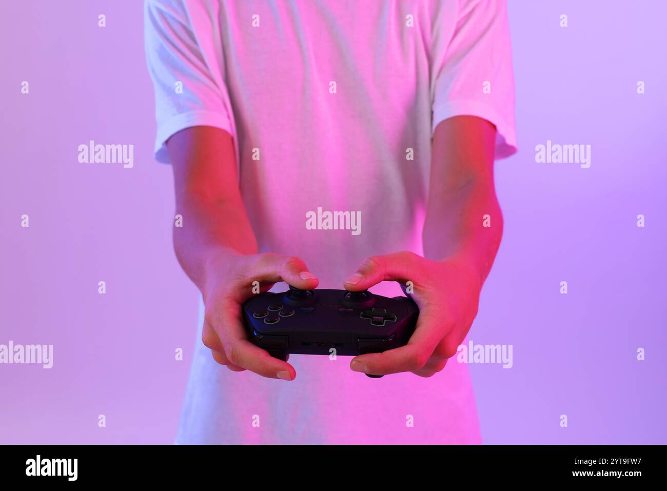 Teenage boy playing video game with controller on violet background ...