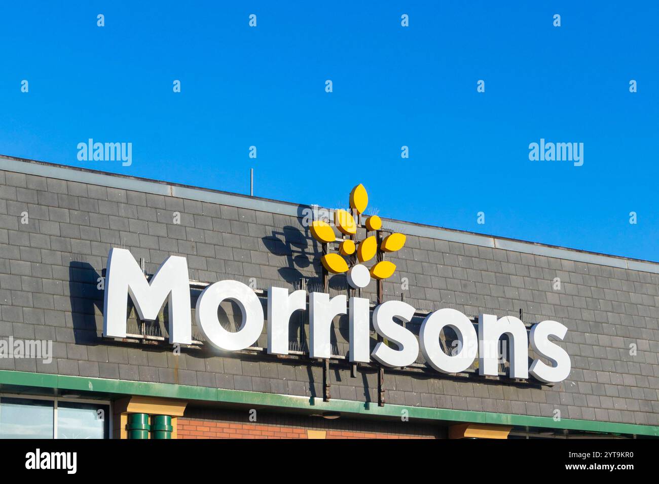 Front view of a Morrisons supermarket sign against a clear blue sky ...