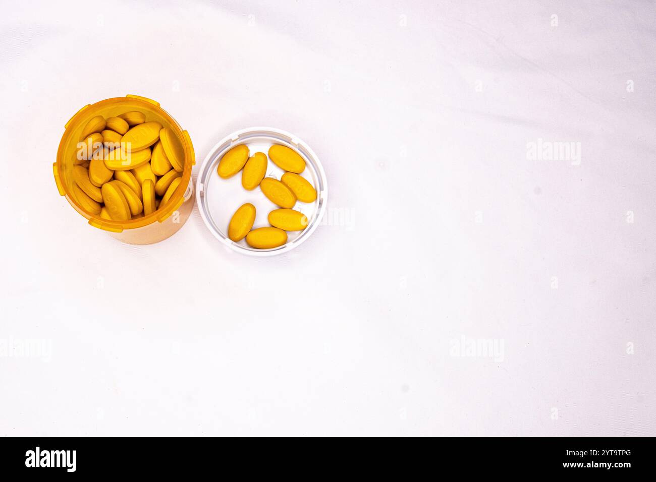 An open bottle of prescription drugs containing orange tablets. The cap ...