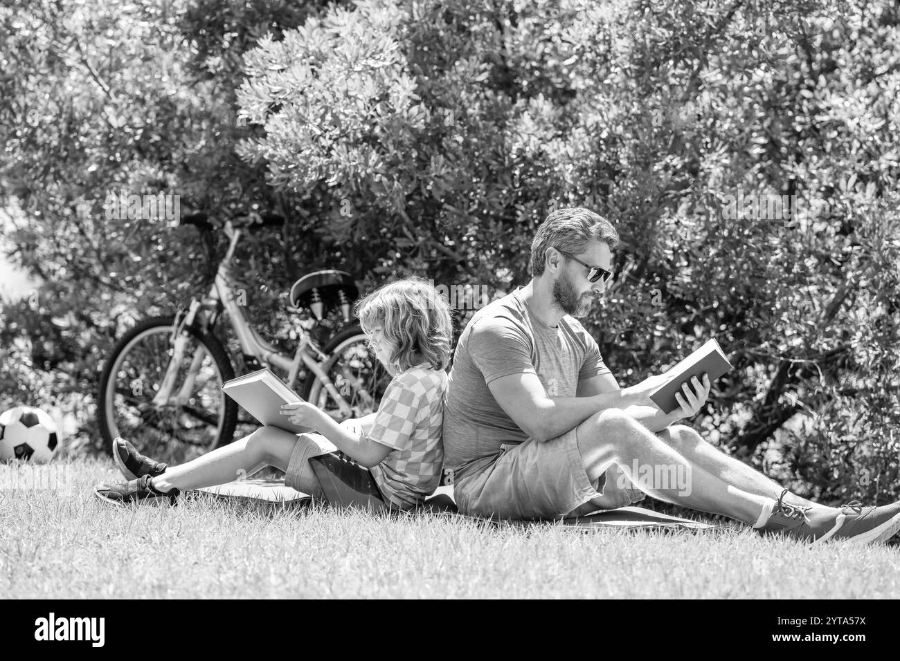 Father and son bonding through outdoor reading. Father and son immersed ...