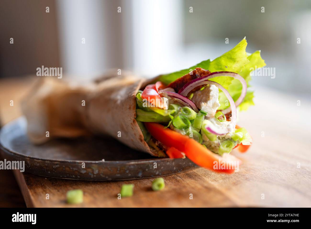 Tortilla wrap with fresh vegatables and fried chicken meat on a plate ...