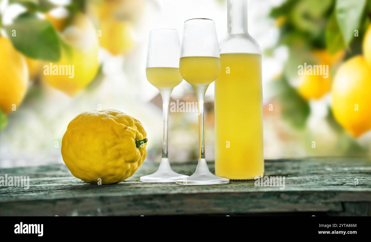 Bottle limoncello and two glasses standing on weathered wooden table ...