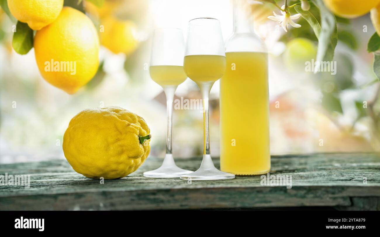 Bottle limoncello and two glasses standing on weathered wooden table ...