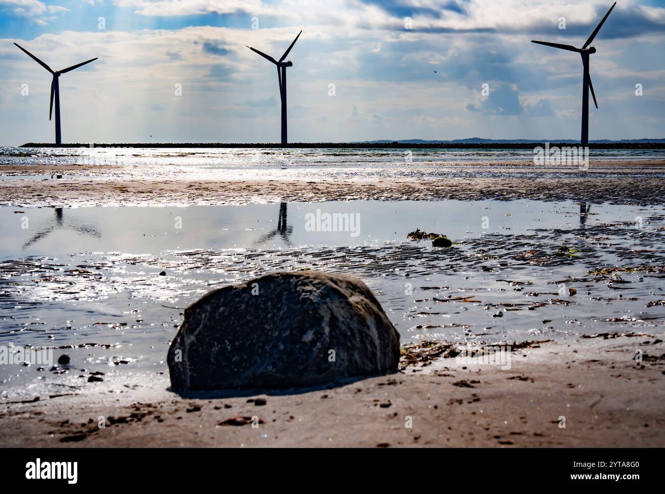 Wind turbine by the sea with glittering sunshine sun and blue sky ...