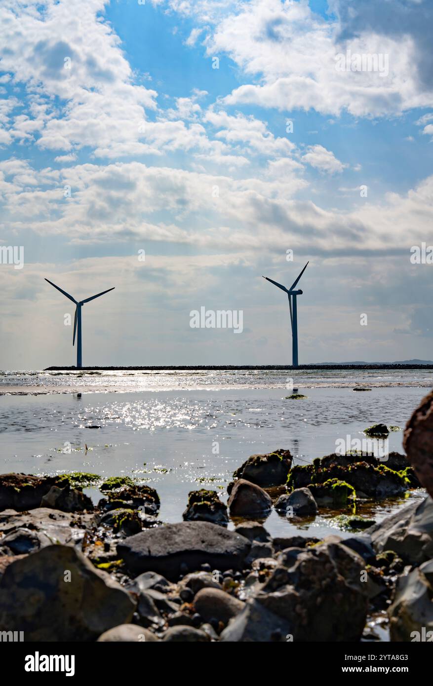 Wind turbine by the sea with glittering sunshine sun and blue sky ...