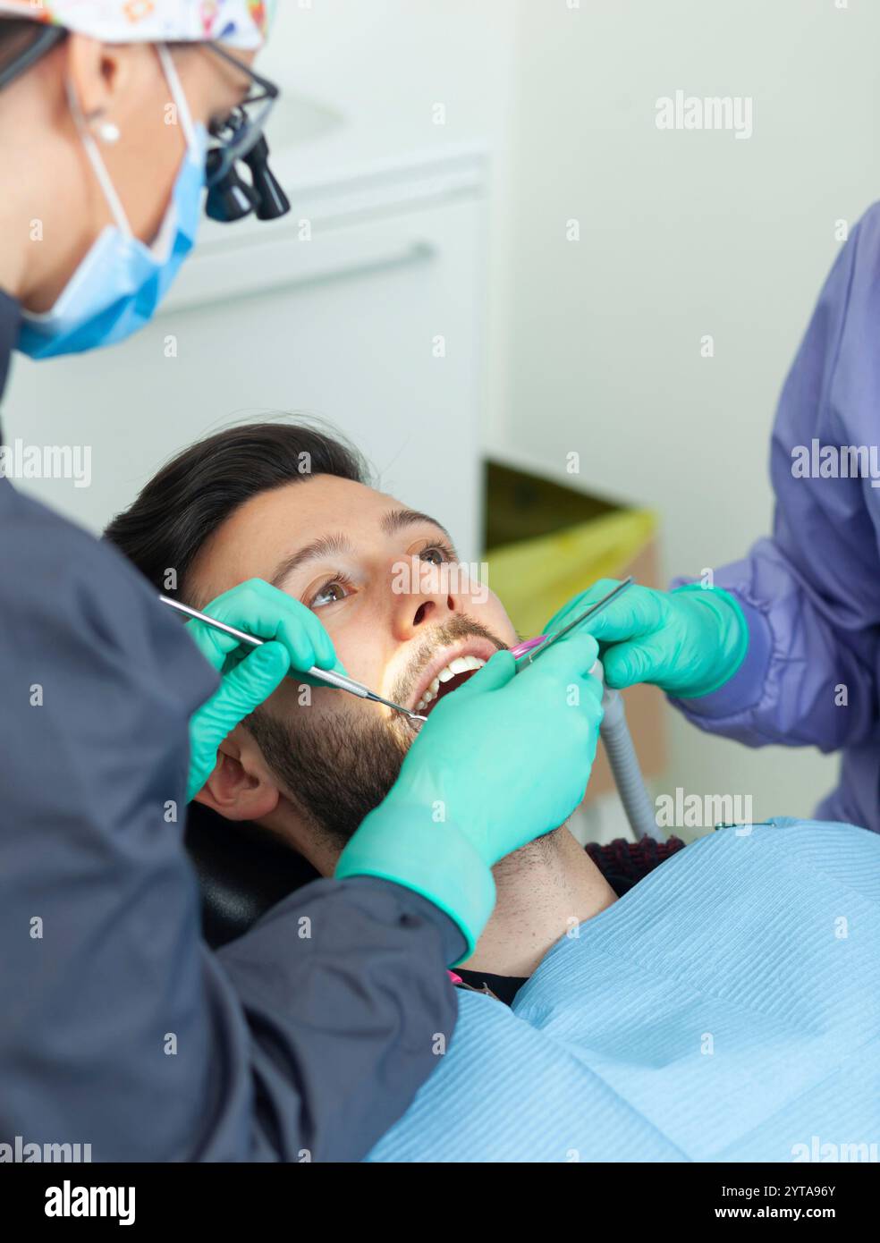 Female dentist examines a man patient in a dental office using ...