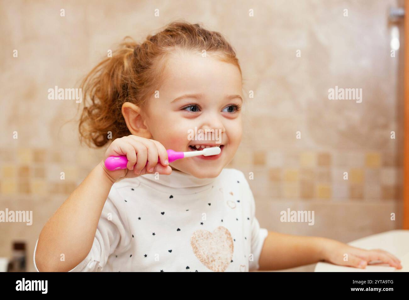 Portrait of cute little girl with blonde hair which cleaning tooth with ...