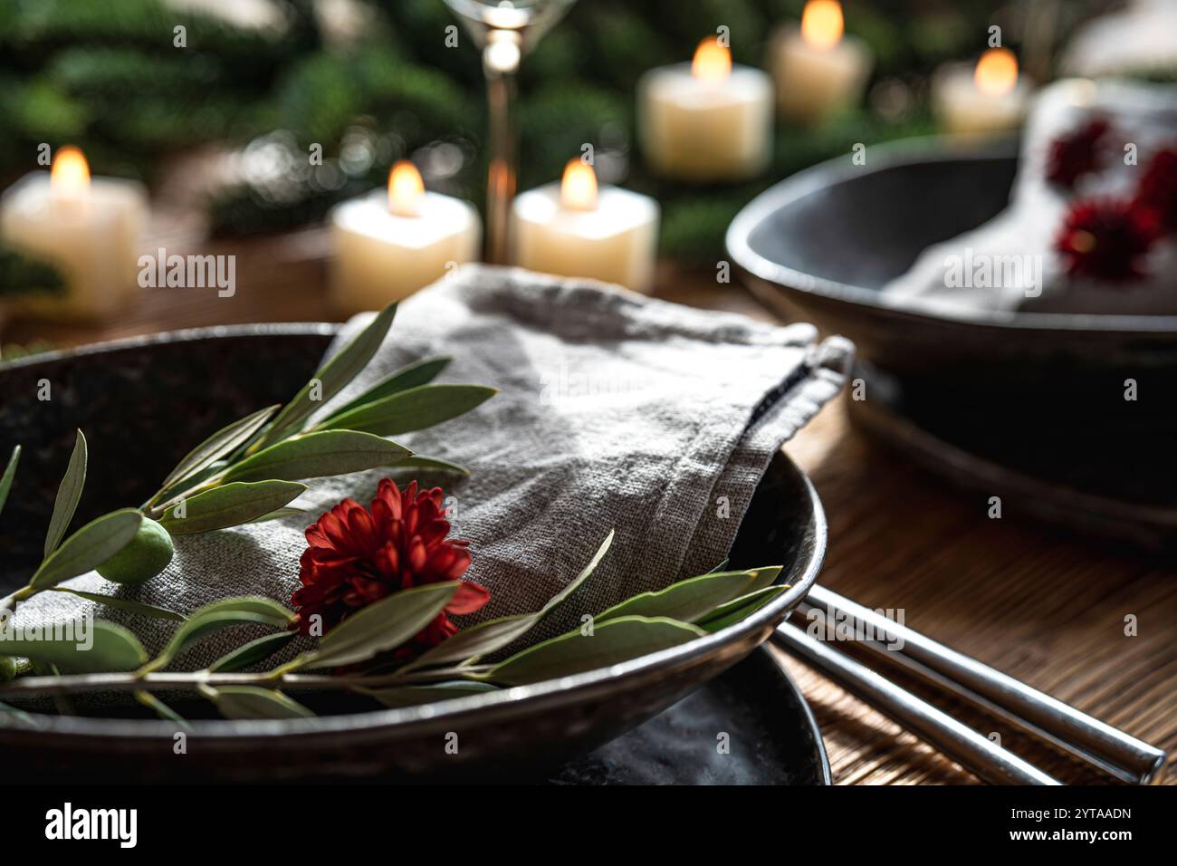 Festive place setting with olive branch and candlelight on a christmas ...