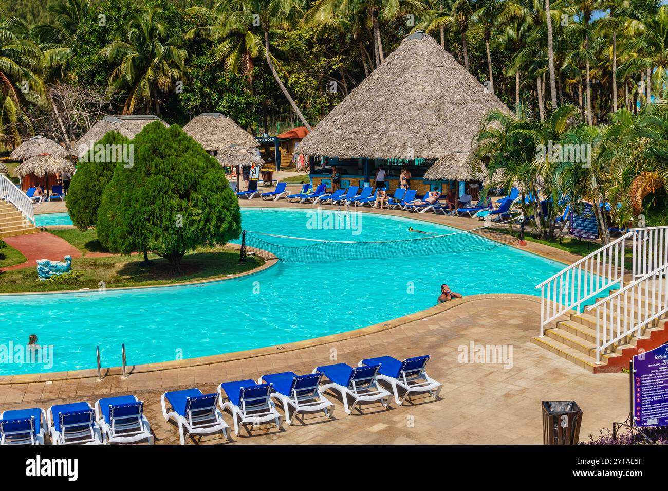 A pool with a beach vibe and lounge chairs. The pool is surrounded by ...