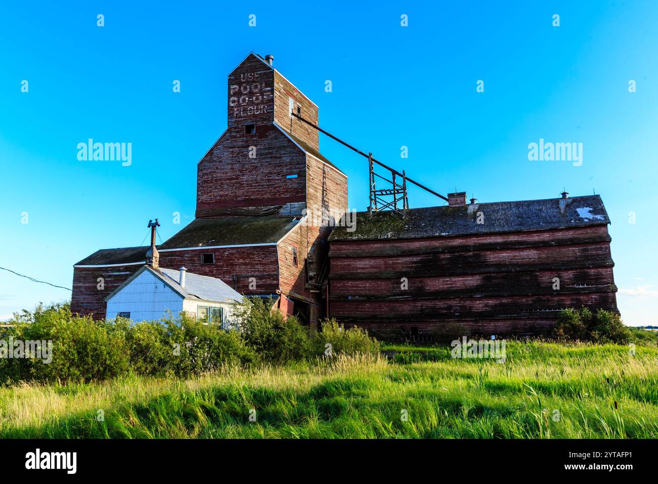 A large red brick building with a white roof sits in a field. The ...