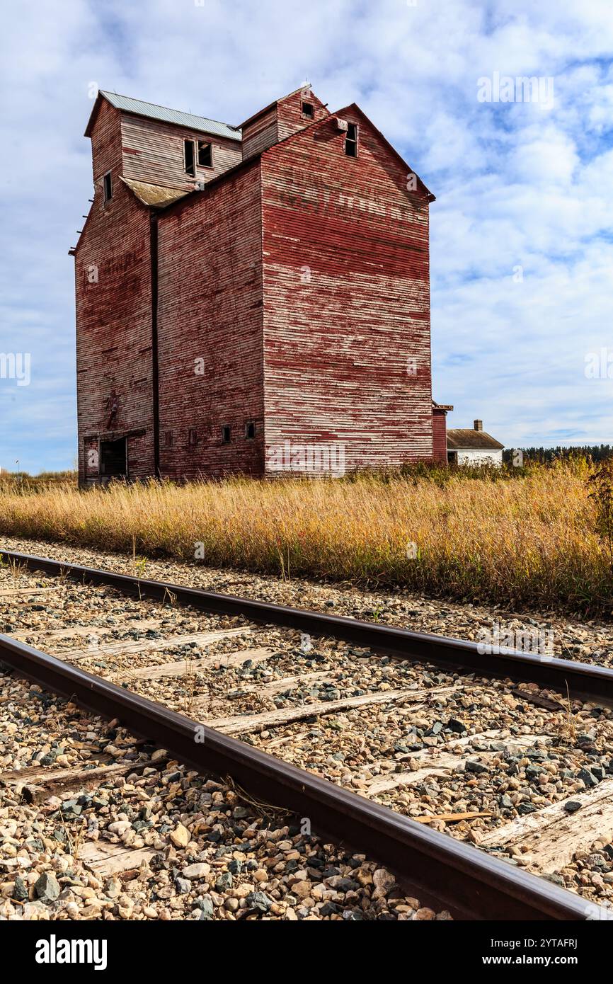 A red barn with a white roof sits on a train track. The barn is old and ...