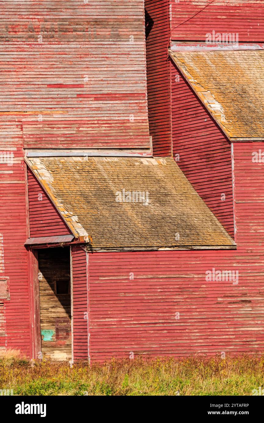 A red barn with a door and a roof. The roof is slanted and has a few ...