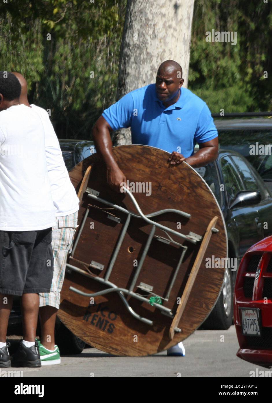 Magic Johnson participates in a community event, carrying supplies and ...