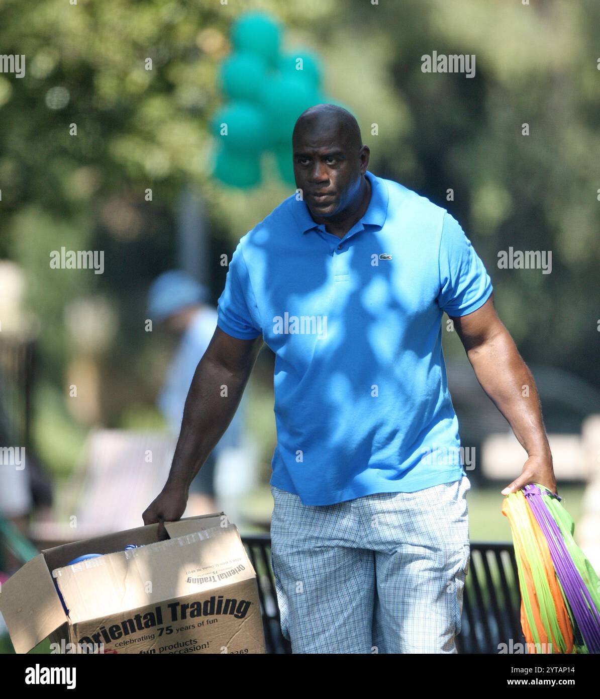 Magic Johnson participates in a community event, carrying supplies and ...