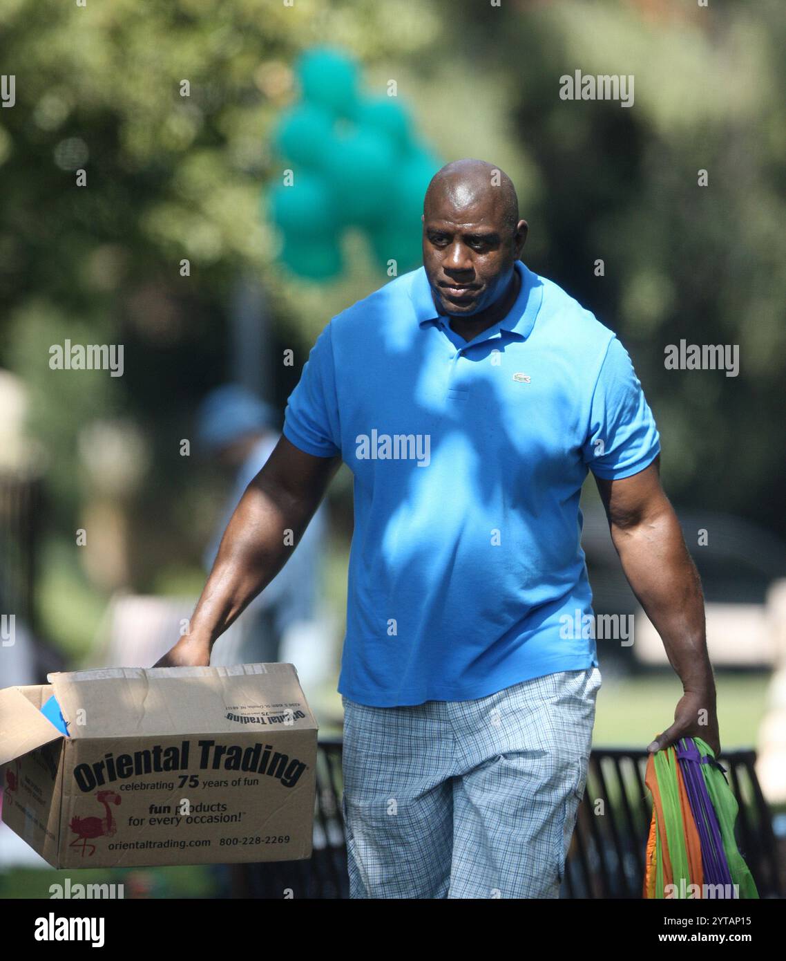 Magic Johnson participates in a community event, carrying supplies and ...