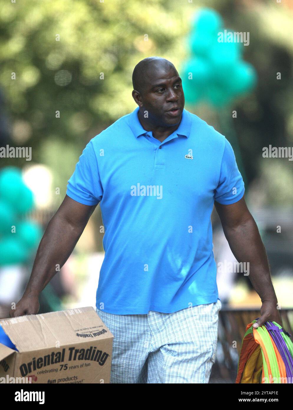 Magic Johnson participates in a community event, carrying supplies and ...