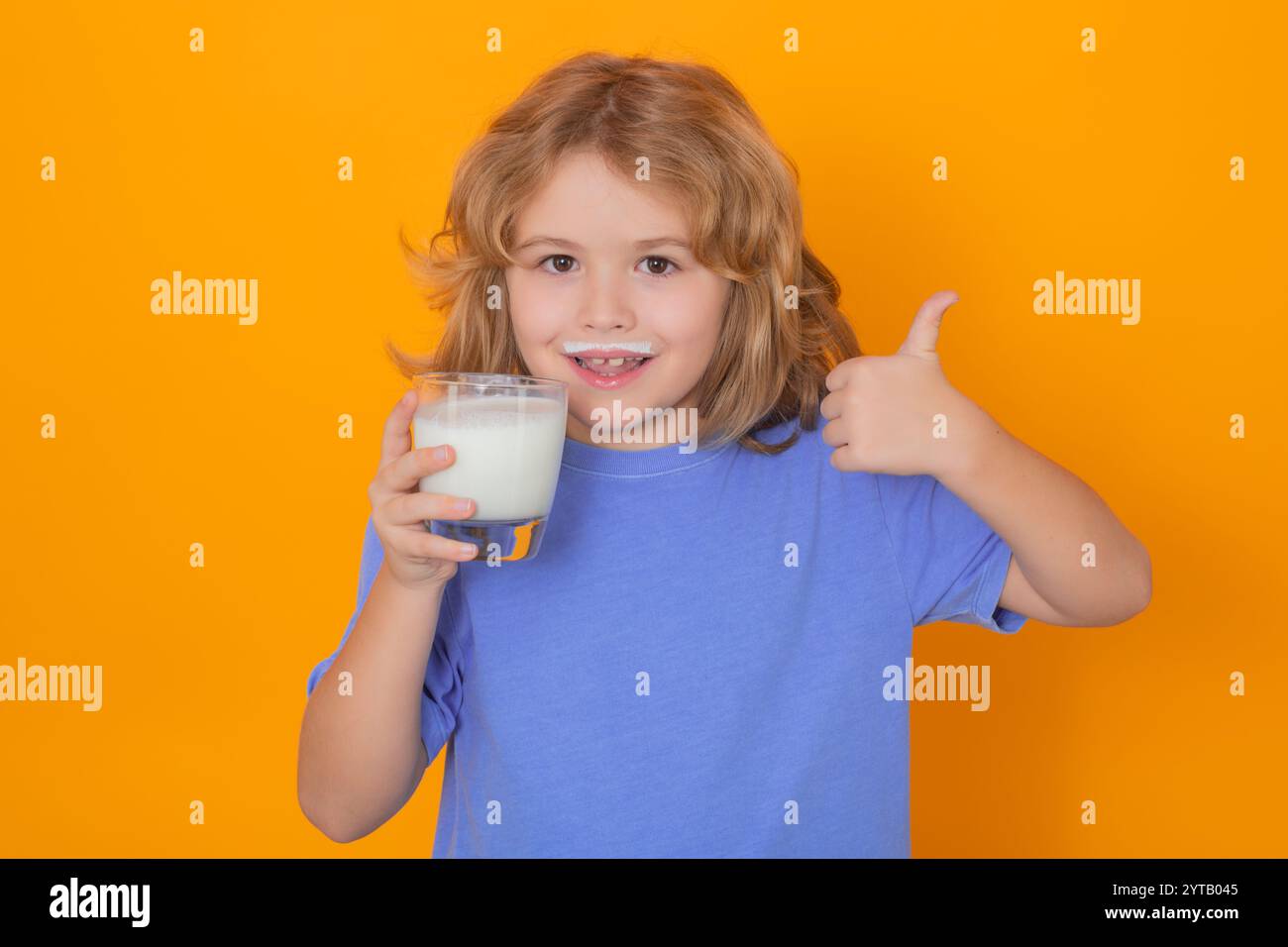 Funny blonde child drinking milk isolated on yellow. Little boy with ...