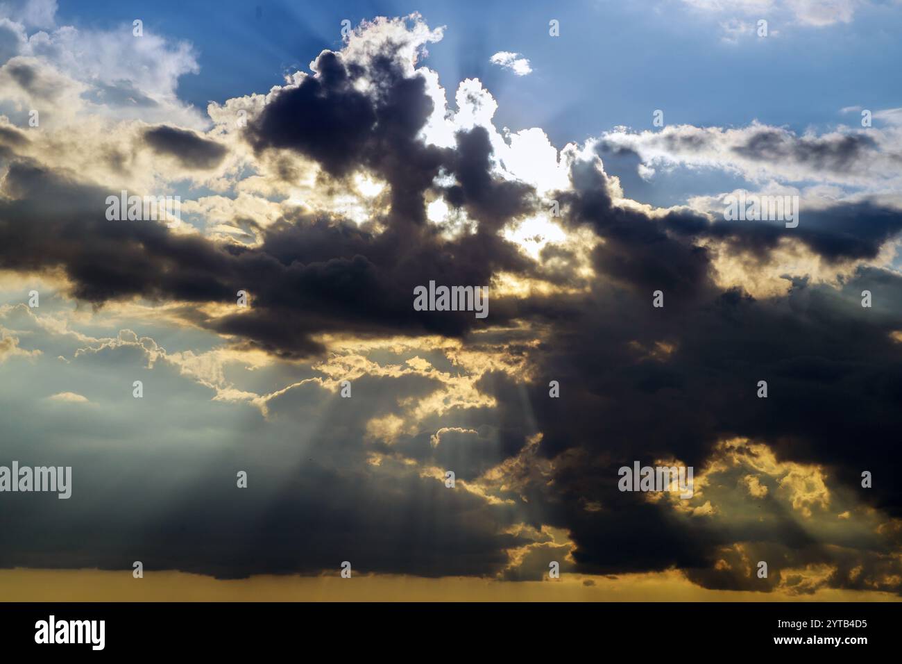 Colorful sunset with dramatic clouds and rays of sunlight breaking through sky over serene ...