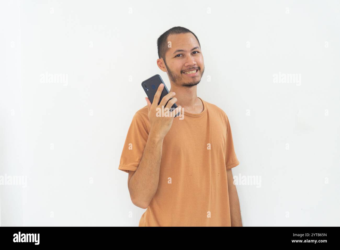 Young men wearing orange shirt is smiling using moble phone on isolated ...