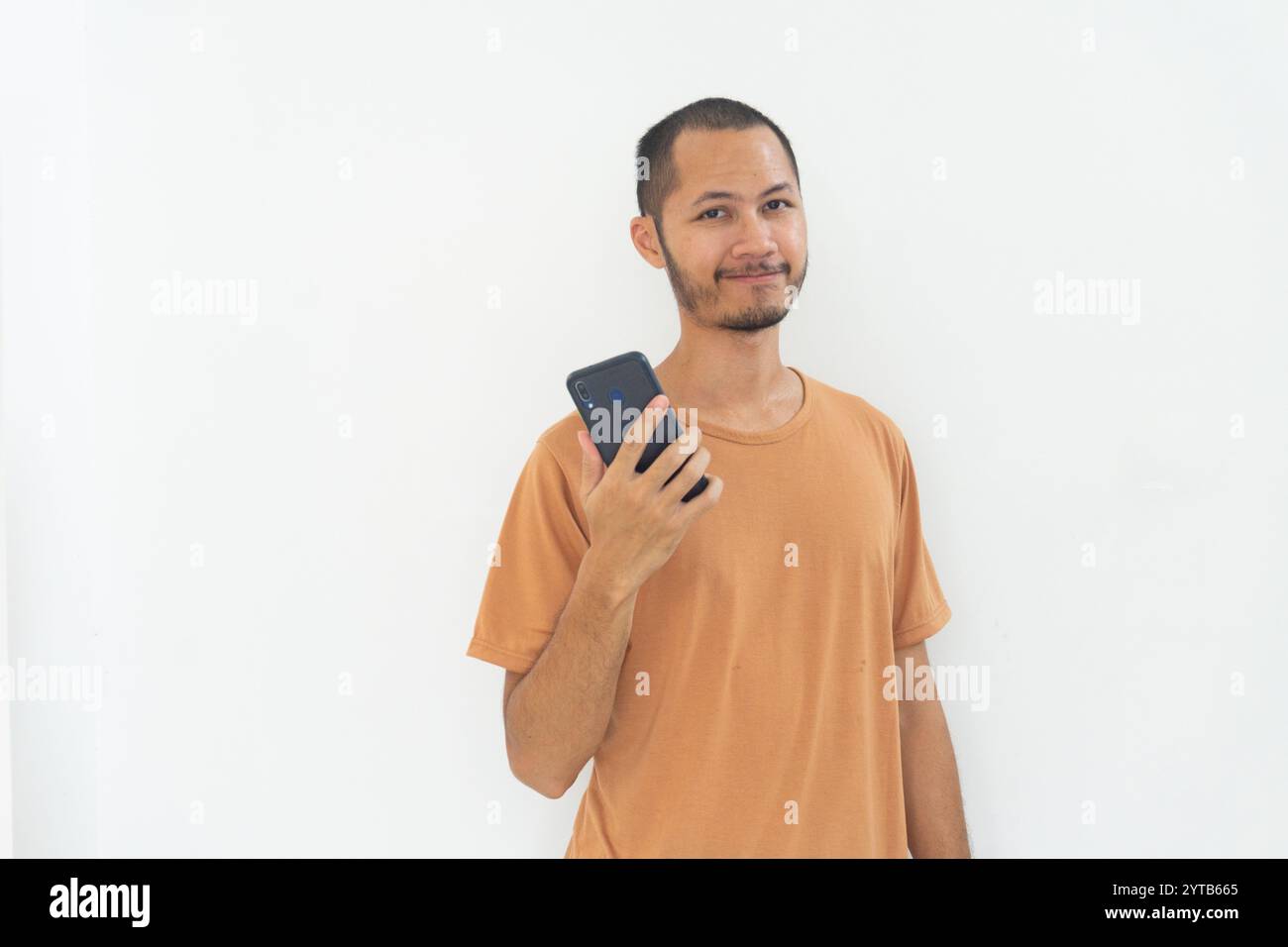 Young men wearing orange shirt is smiling using moble phone on isolated ...