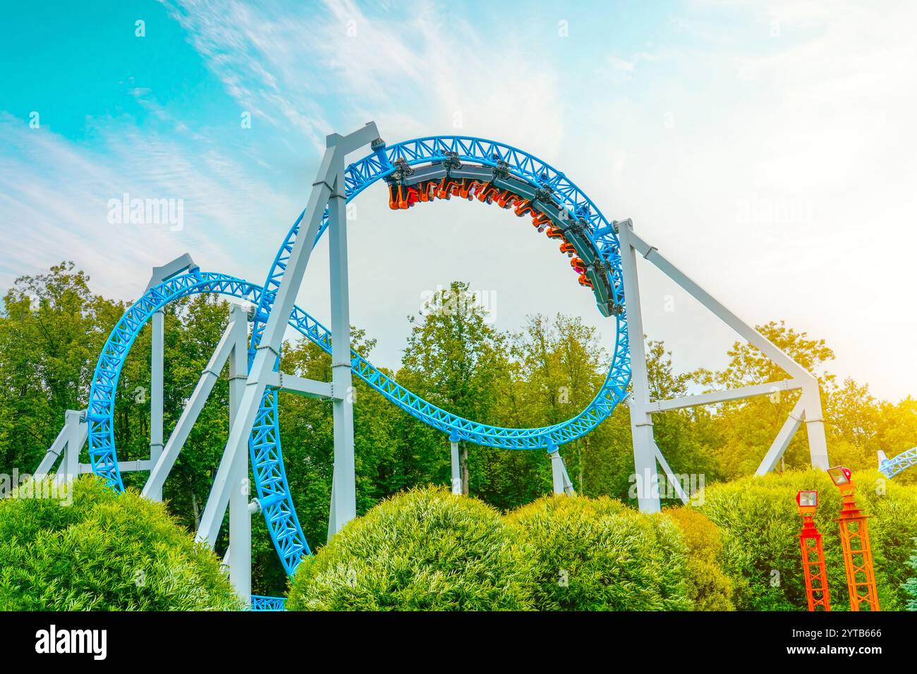 Roller coaster cart with people riding it goes through a loop upside ...