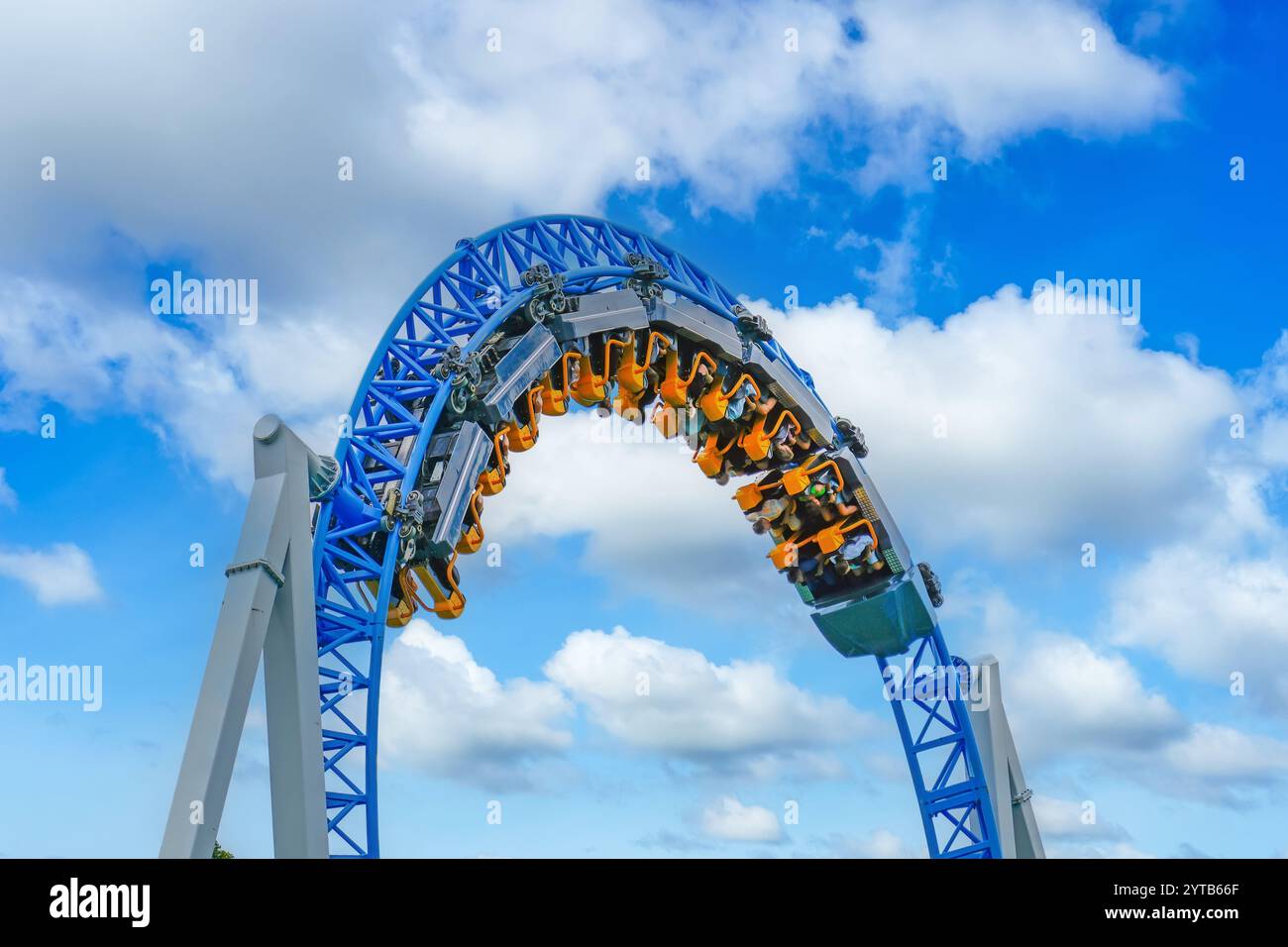Roller coaster cart with people riding it goes through a loop upside ...