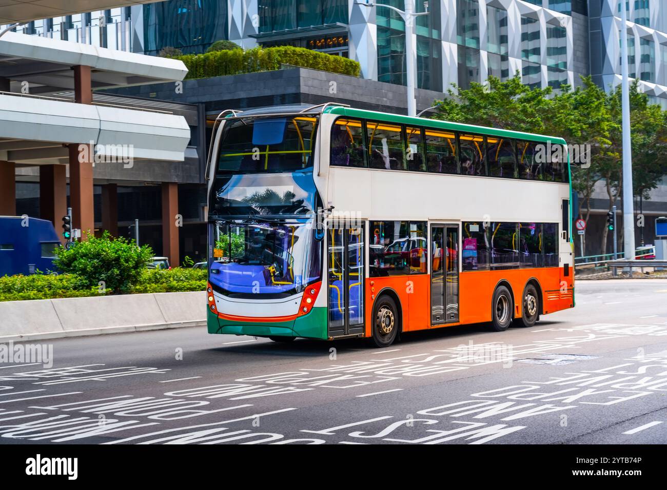 Double-decker city shuttle bus drives along route line among buildings ...
