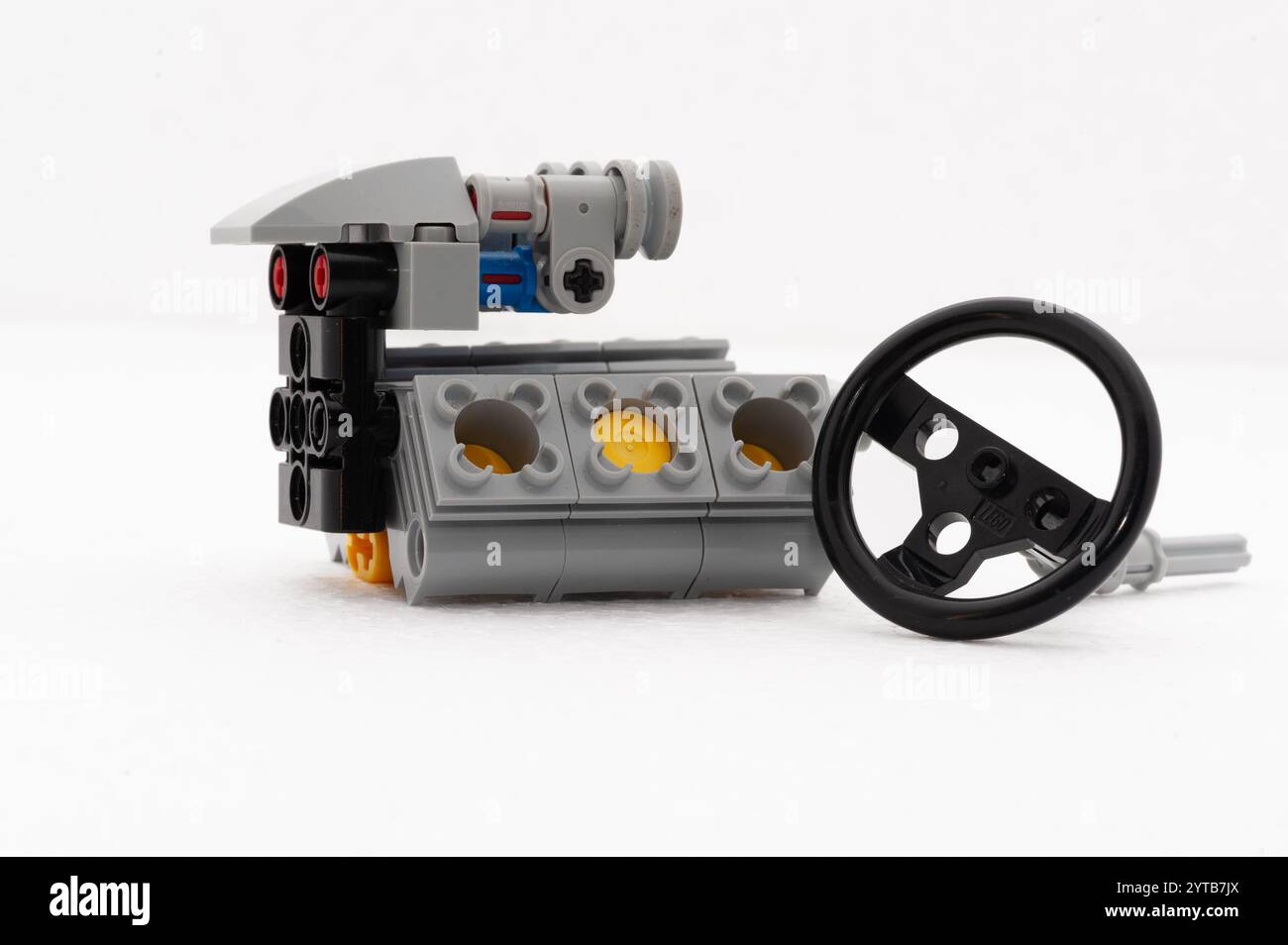 A toy car engine with a steering wheel. The engine is on a white ...