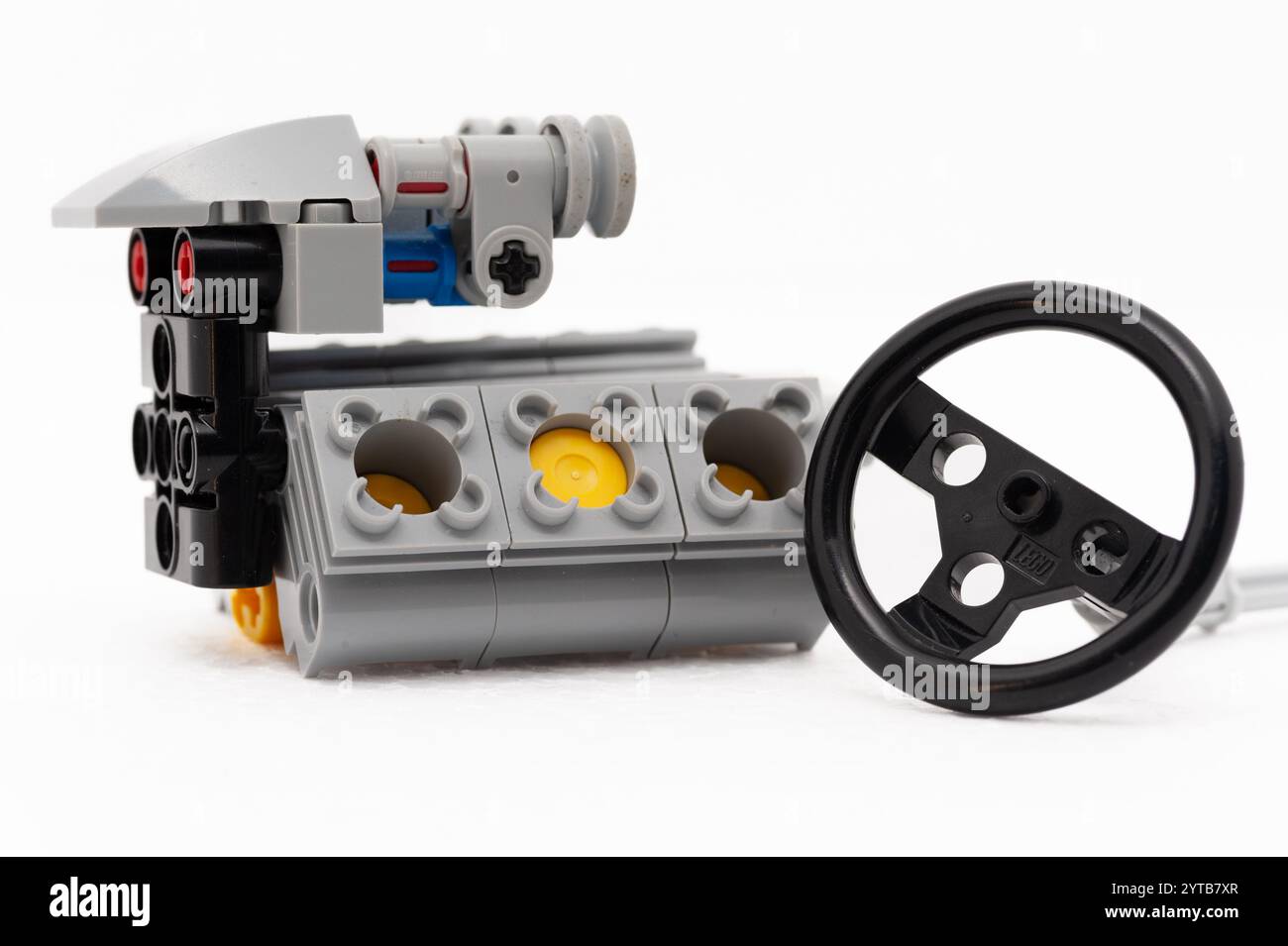 A toy car engine with a steering wheel. The engine is on a white ...