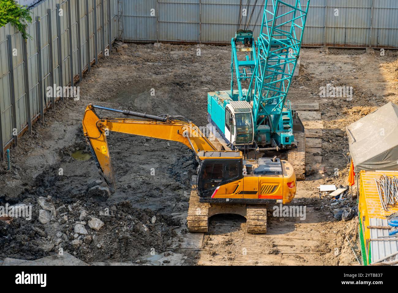 Excavators during earthworks at construction site. Backhoe the digging pit for construct ...