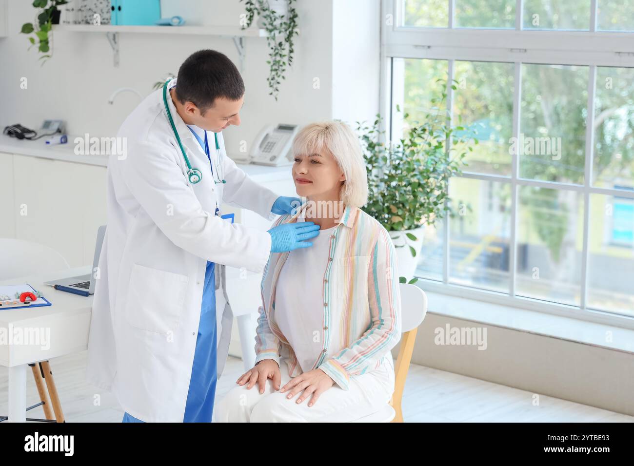 Male endocrinologist examining thyroid gland of female patient in ...