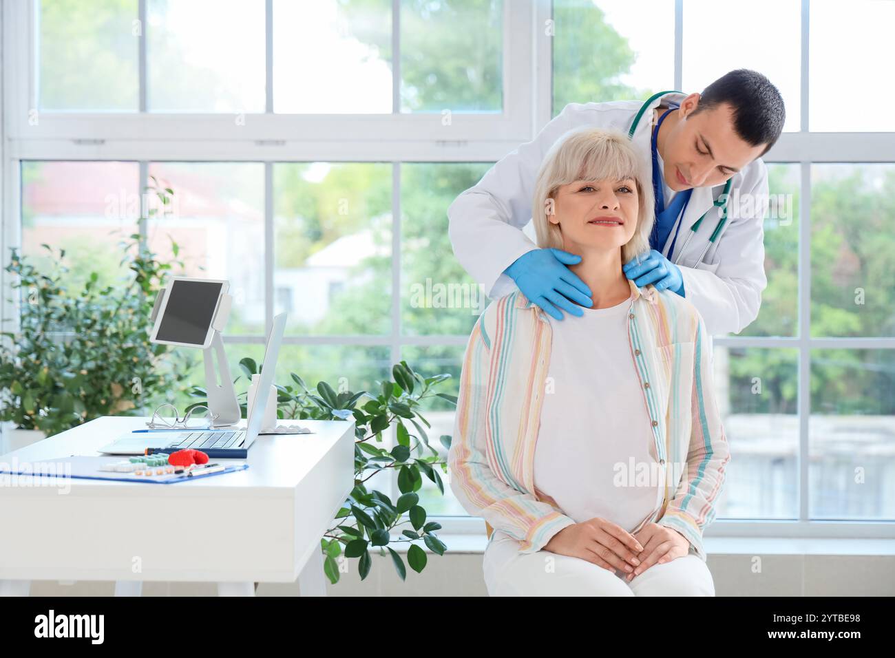 Male endocrinologist examining thyroid gland of female patient in ...