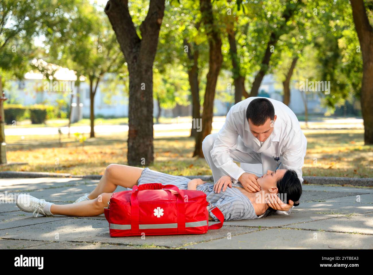 Male doctor checking pulse of unconscious woman having heart attack in ...
