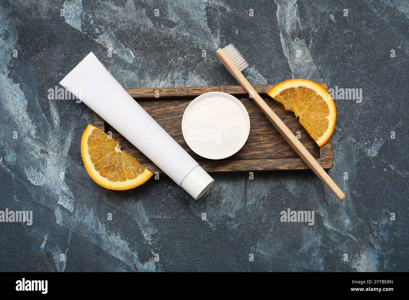 Bowl of tooth powder with citrus slices, toothpaste and brush on tray ...