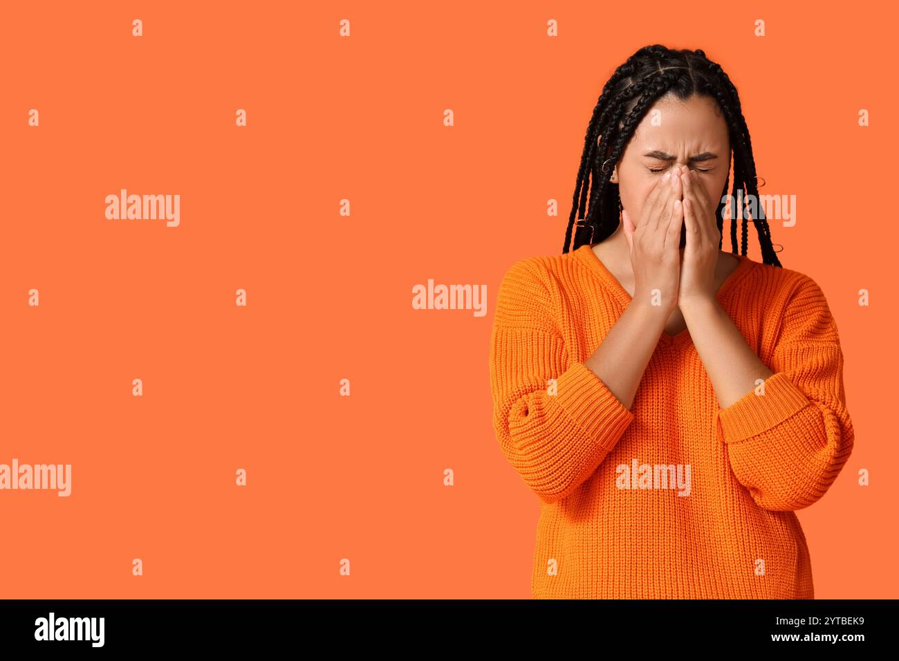Beautiful young sad African-American woman crying on orange background ...