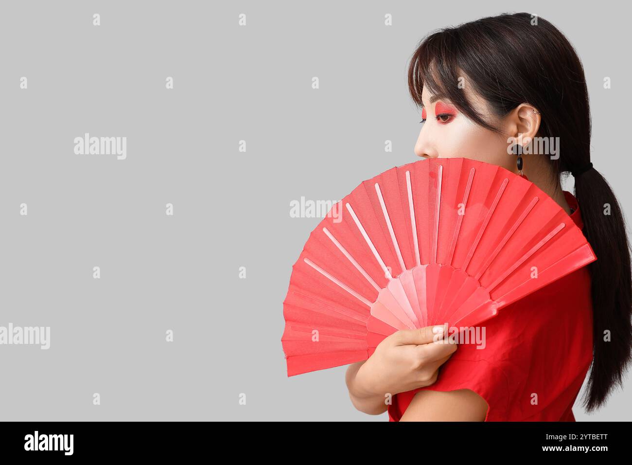 Beautiful young geisha in traditional clothes with fan on grey ...