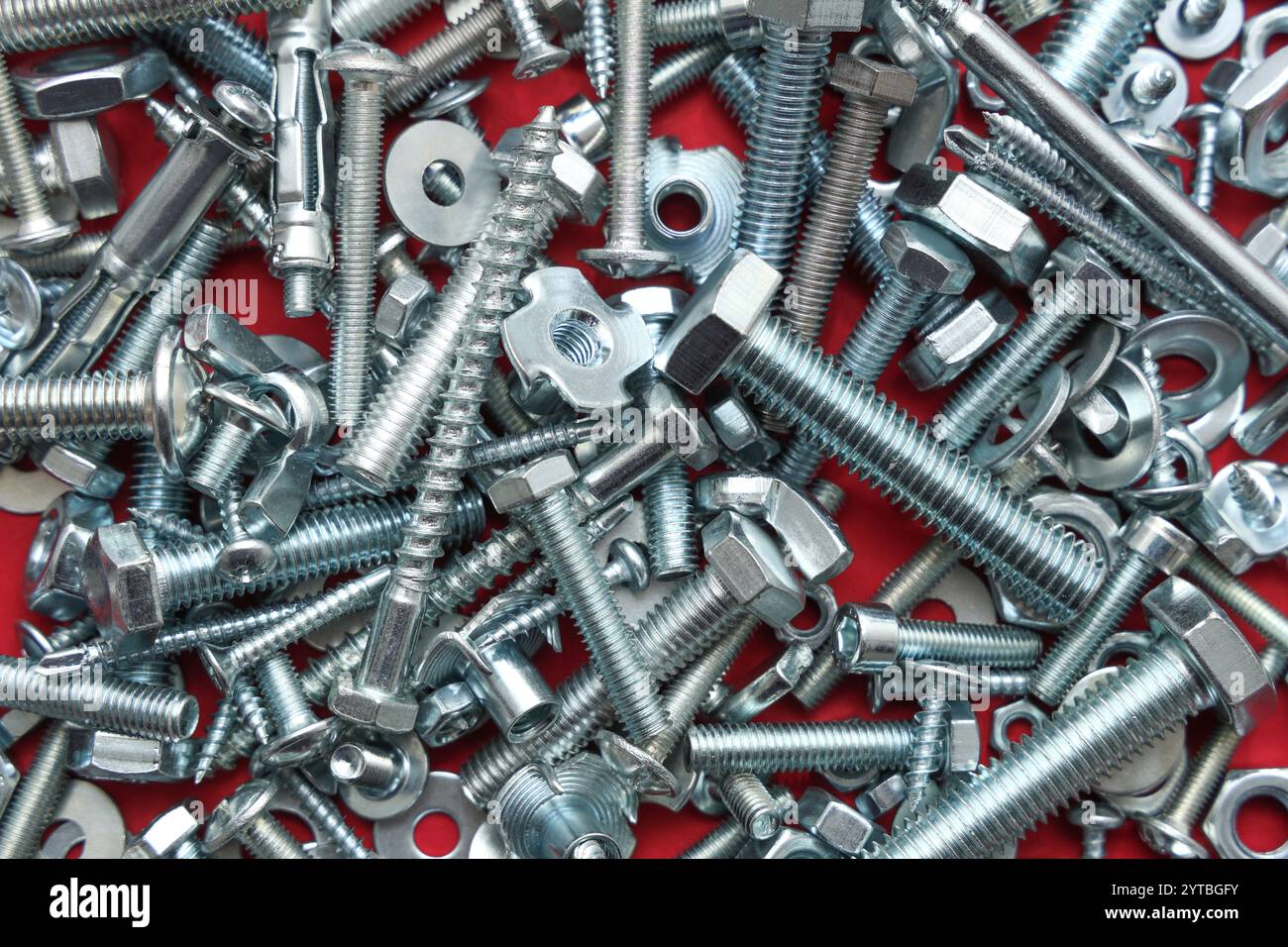 Different tap bolts, screws and chrome nuts on red background Stock ...