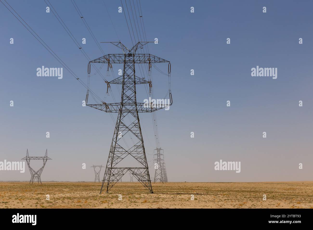 High voltage transmission towers stretch across the barren terrain of ...