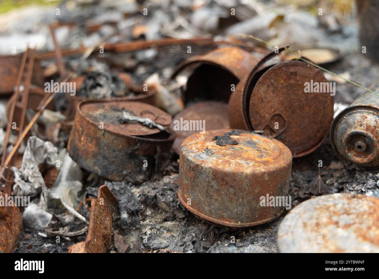 Old, rusted metal cans in burned ash. Trash in abandoned army base ...