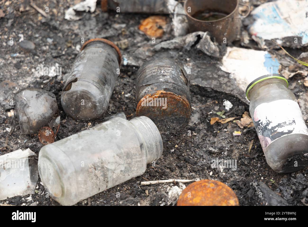 Old, rusted metal cans in burned ash. Trash in abandoned army base ...