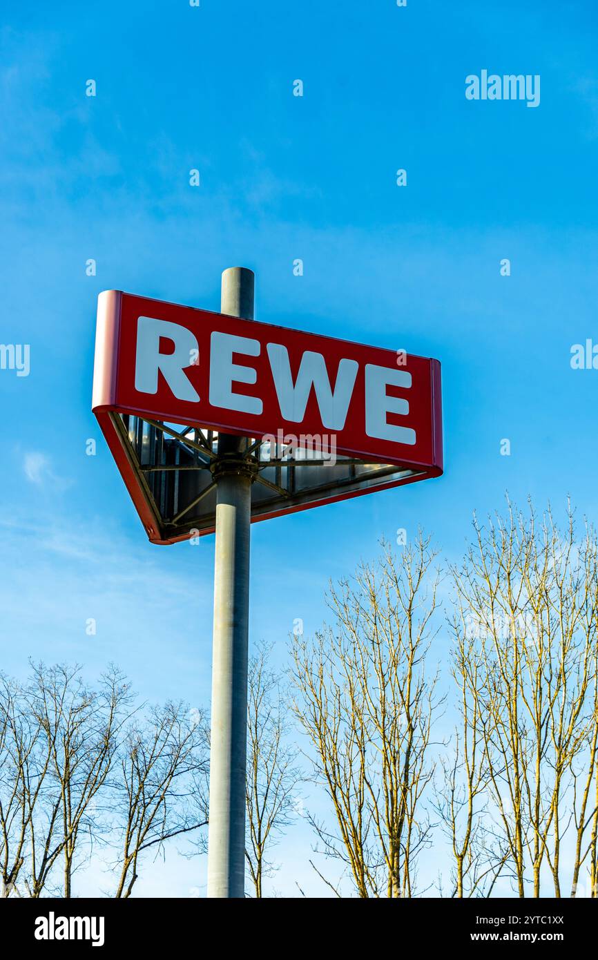Logo of the German supermarket chain Rewe in front of a blue sky in Bad ...