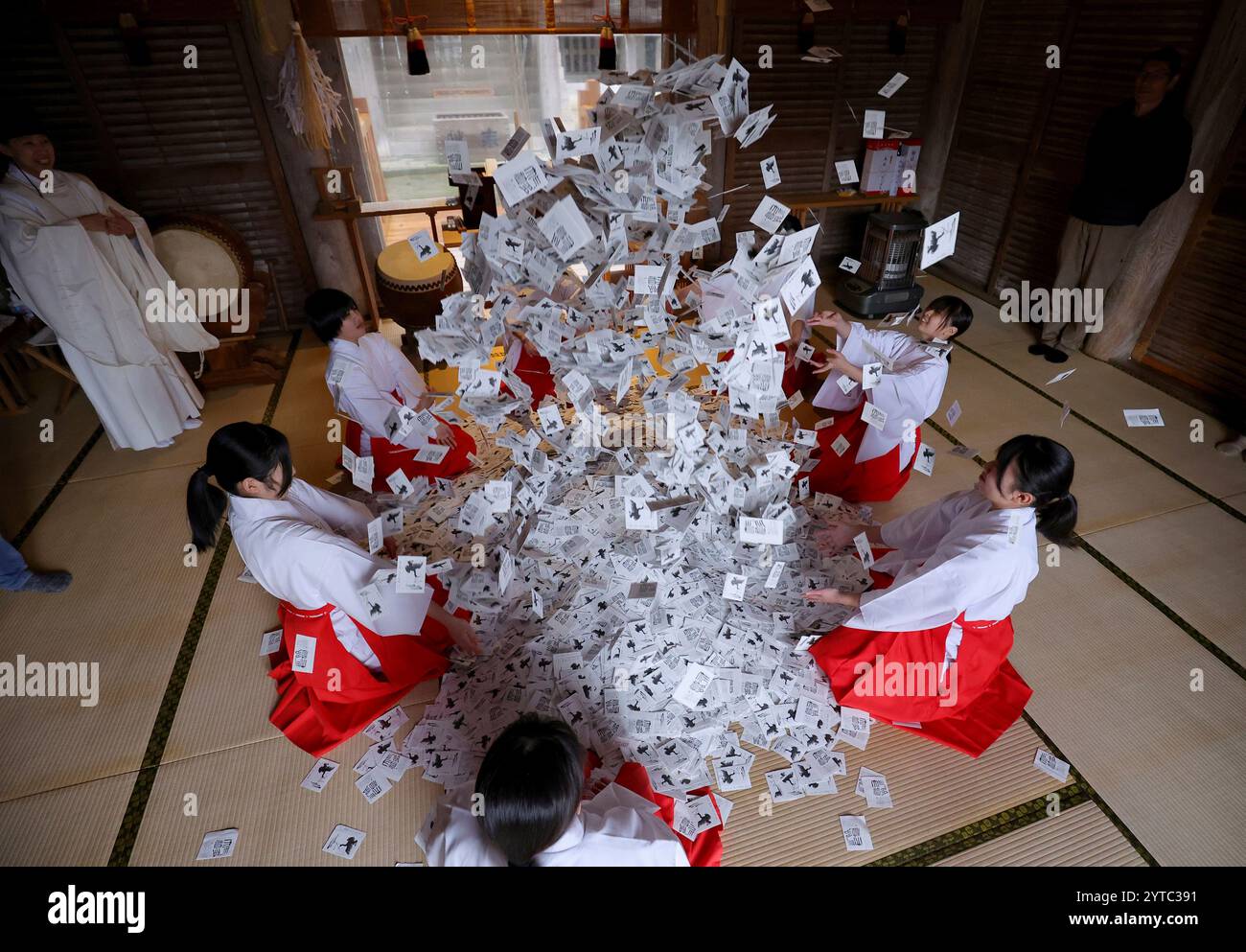 Female students dressed as shrine maidens throw up "Omikuji" (a type of ...