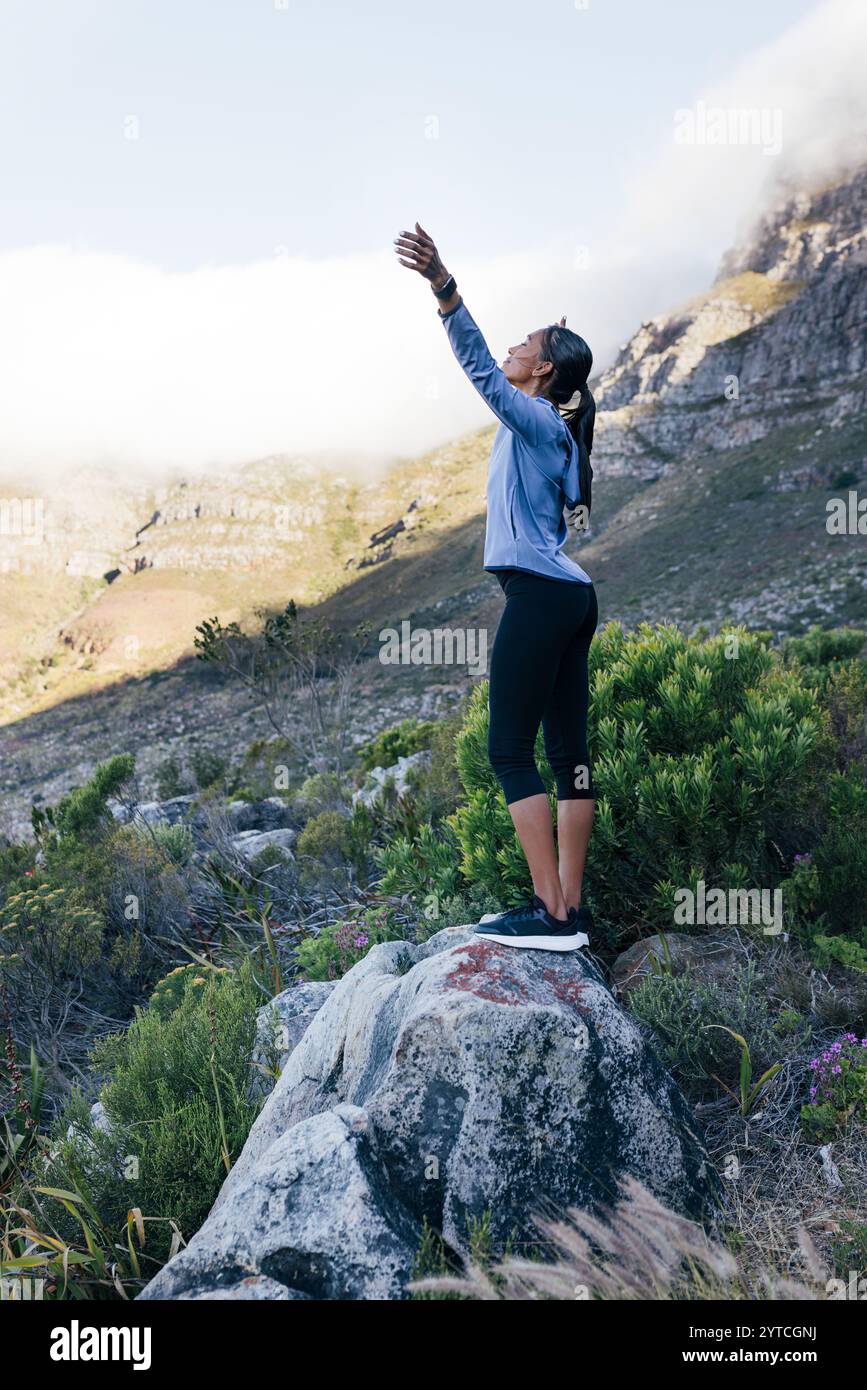 Full-length female trail runner enjoying nature. Young woman raising ...
