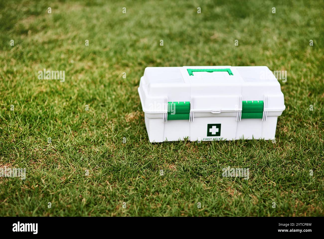 First aid, kit and grass field with medical supplies for sports injury ...