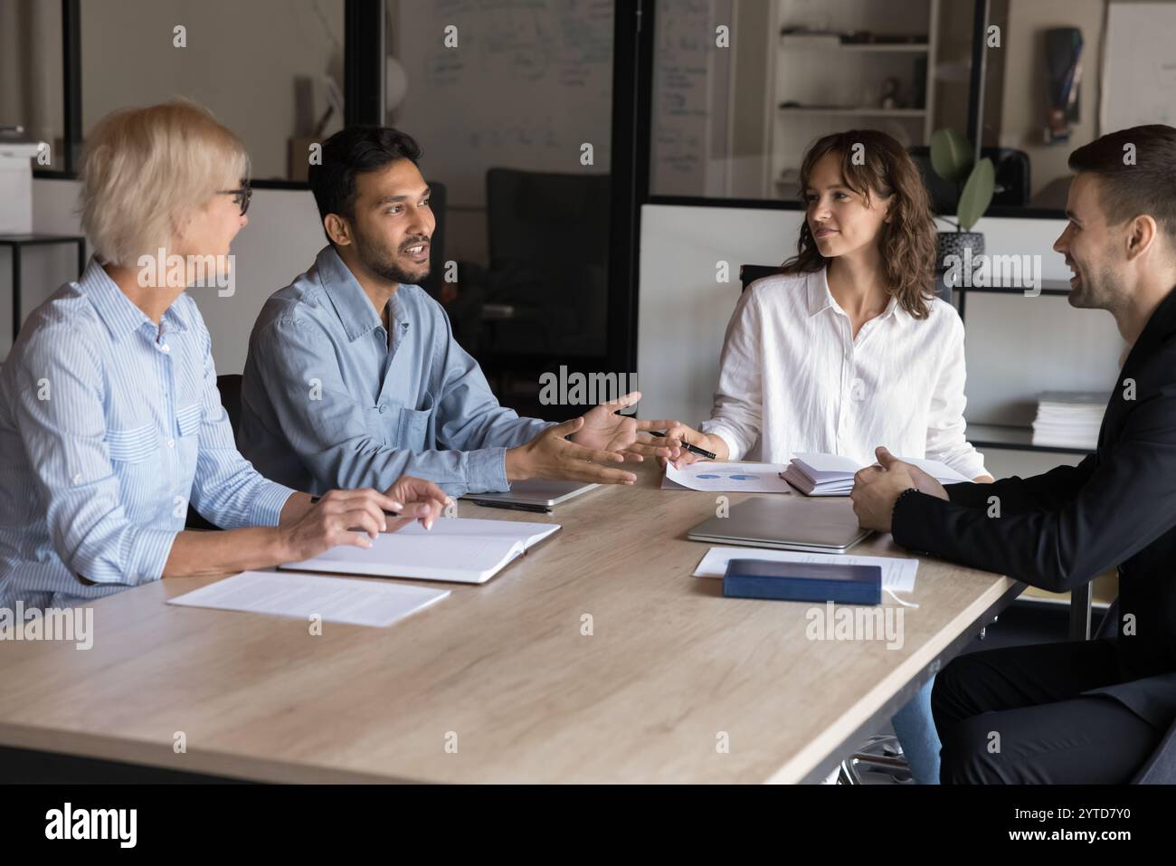 Group of four professionals engaged in meeting around conference table ...