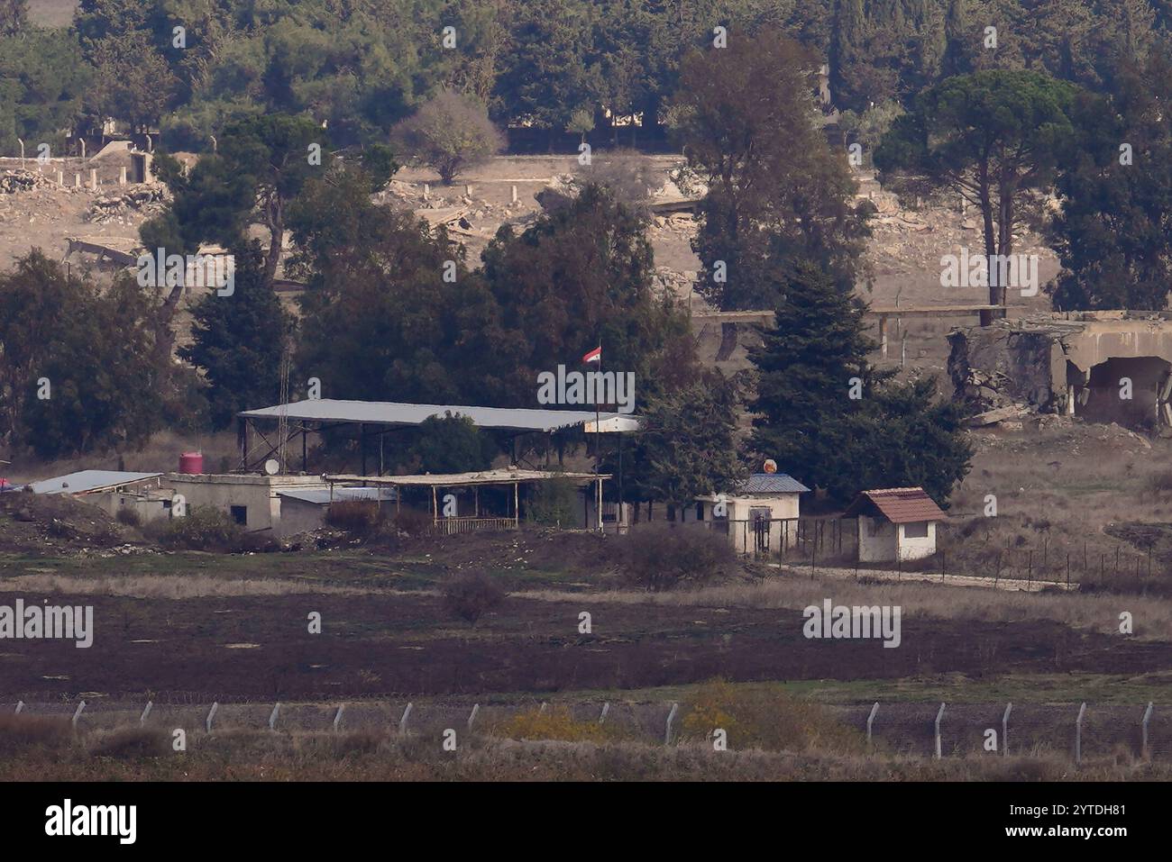 The official flag of the Syrian government flies at the Syrian post at ...