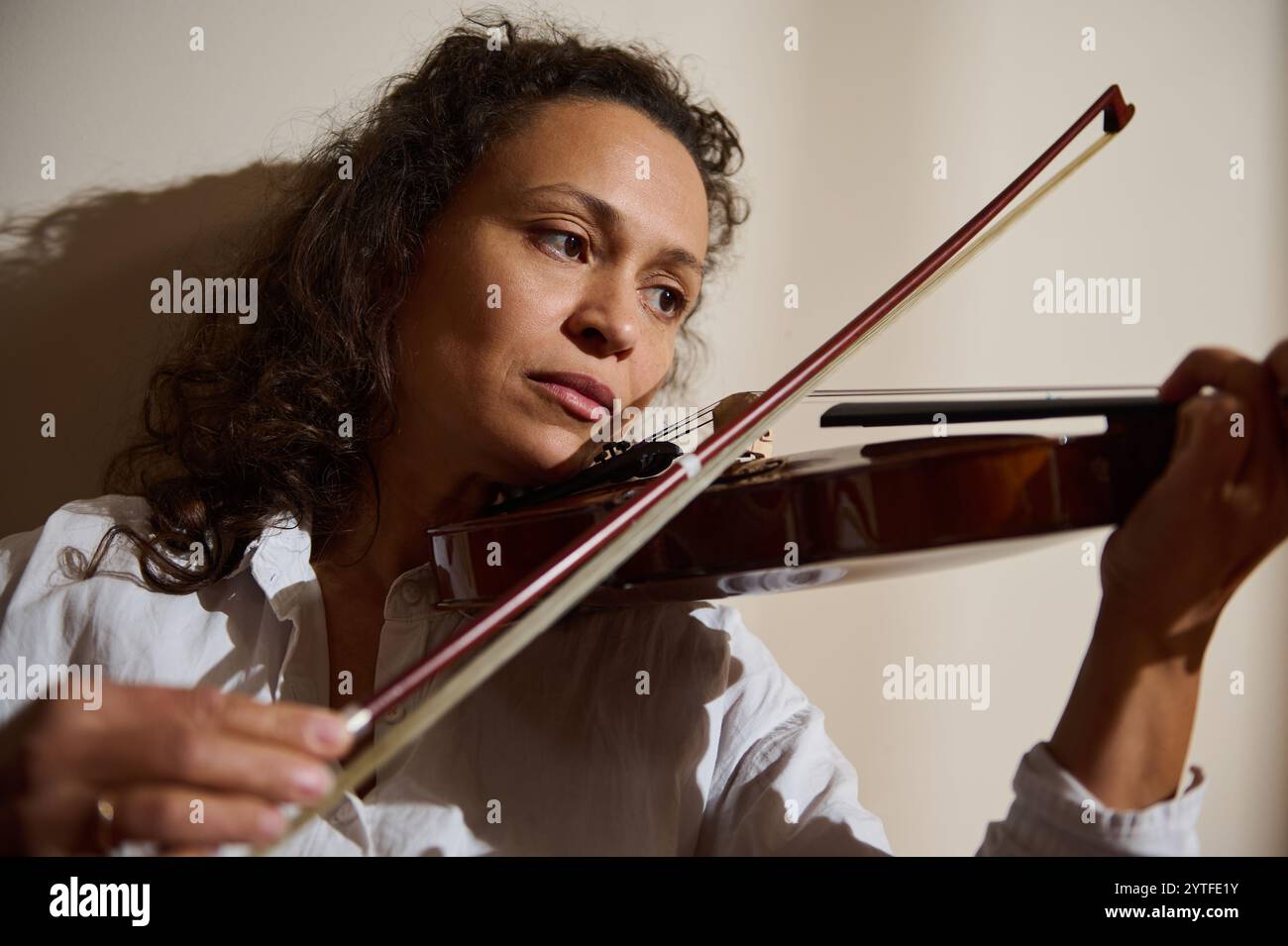 A woman intently plays the violin, showcasing passion and focus under ...